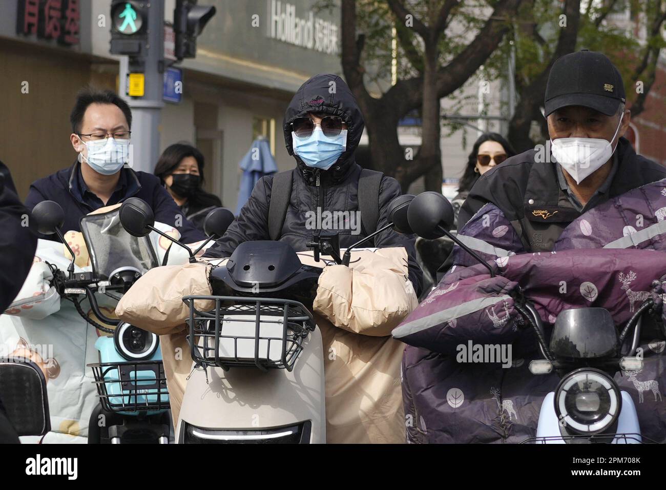 People wearing masks ride motorcycles in Beijing on April 12, 2023 ...