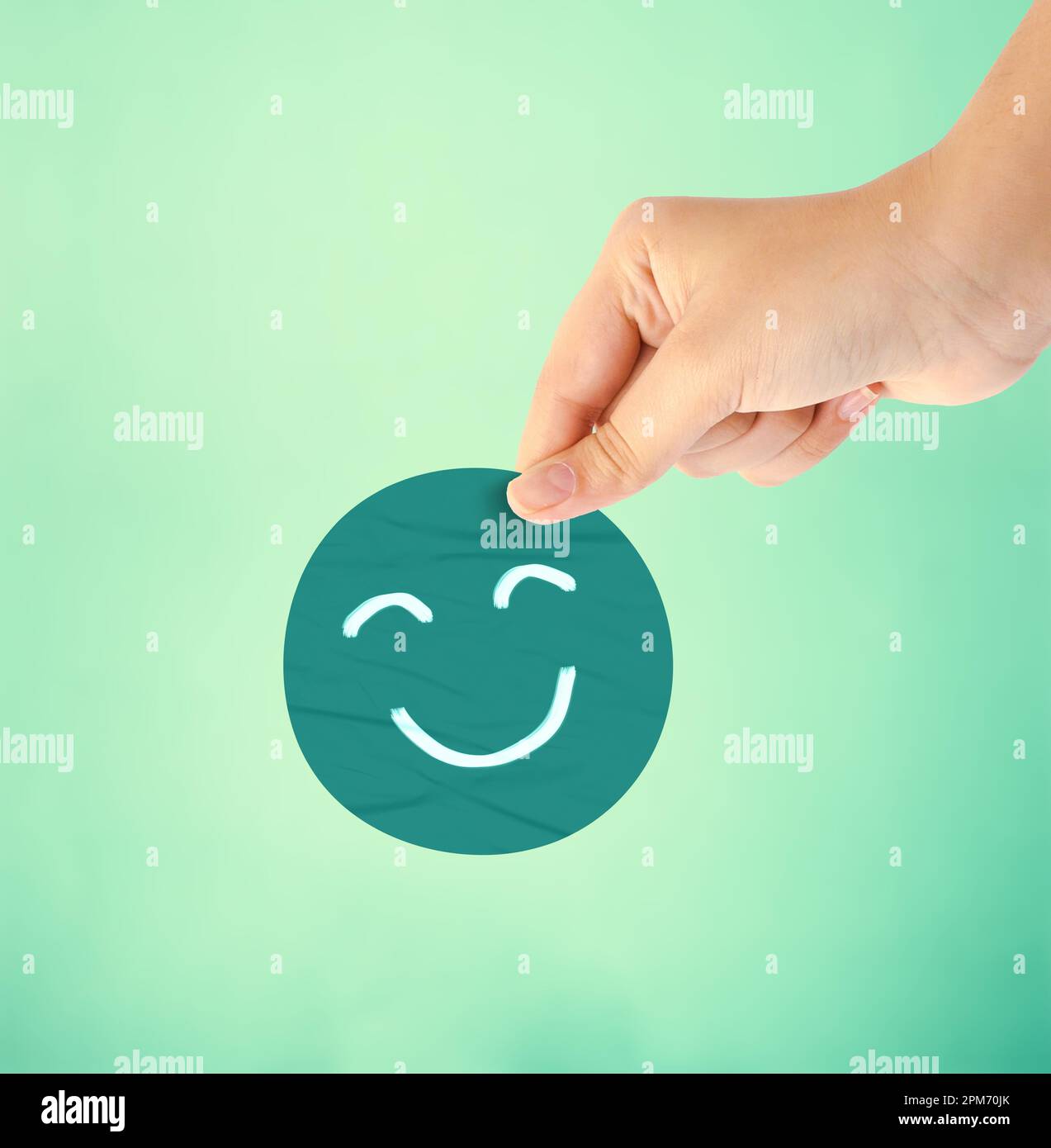 Hand holding blue happy smile face paper cut Stock Photo - Alamy