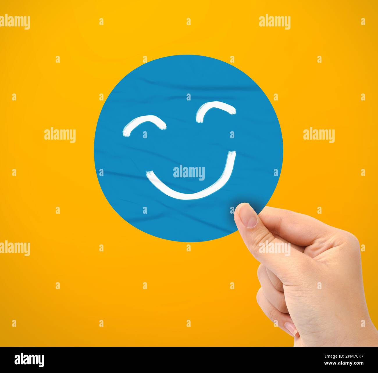 Hand holding blue happy smile face paper cut on yellow background Stock ...