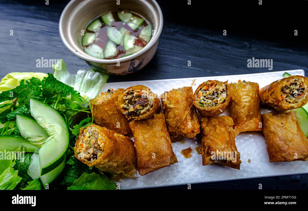 Vietnamese spring rolls sliced up on a long white plate with a side of ...