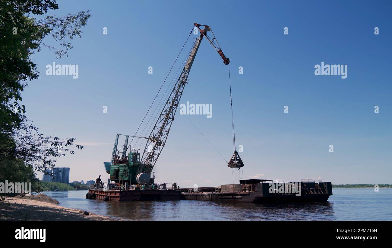 View of a floating crane unloading sand from a moored barge onto the ...