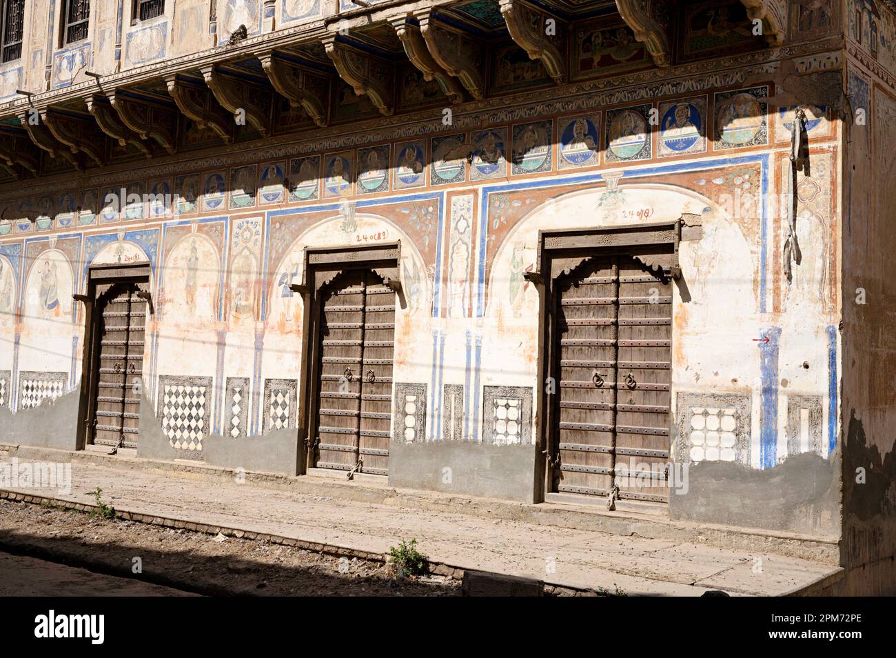 Carved wooden doors and colourful paintings on the outer wall of an old ...