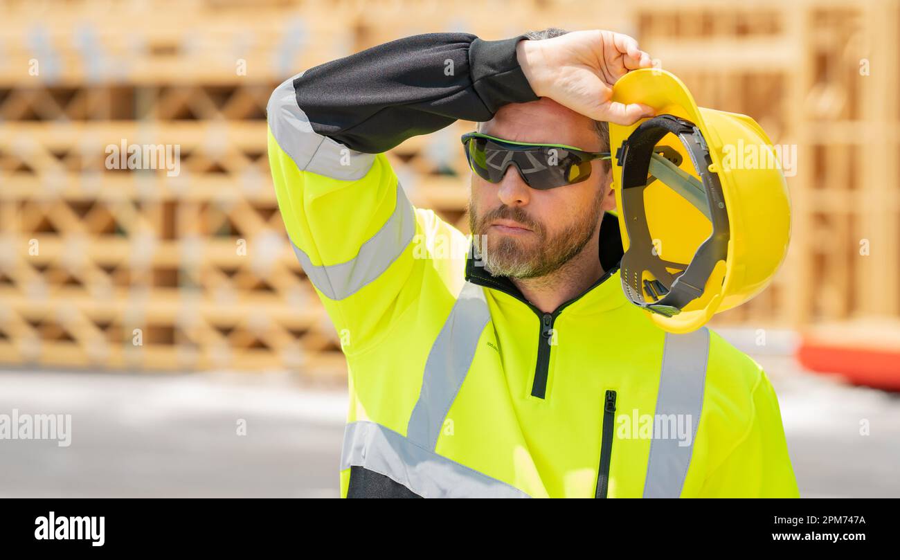 Tired, overworked worker in building uniform on buildings construction ...