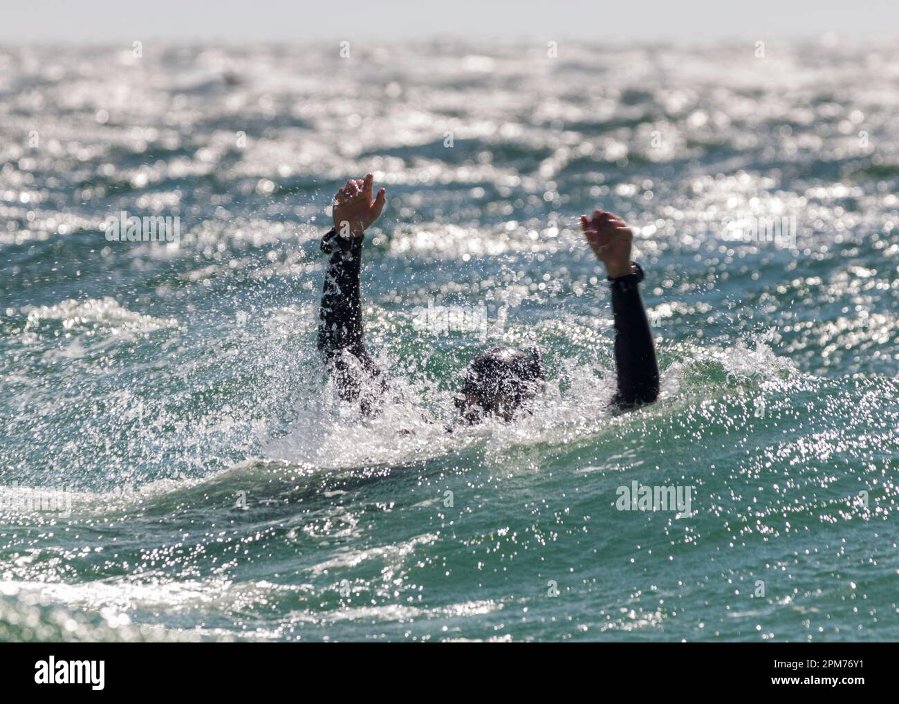 A scuba diver in distress signals in the sea with arms in the air ...