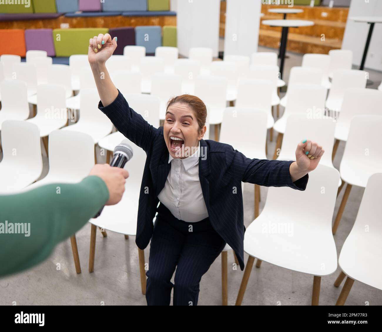 A red-haired Caucasian business woman sits in the front row in an empty ...