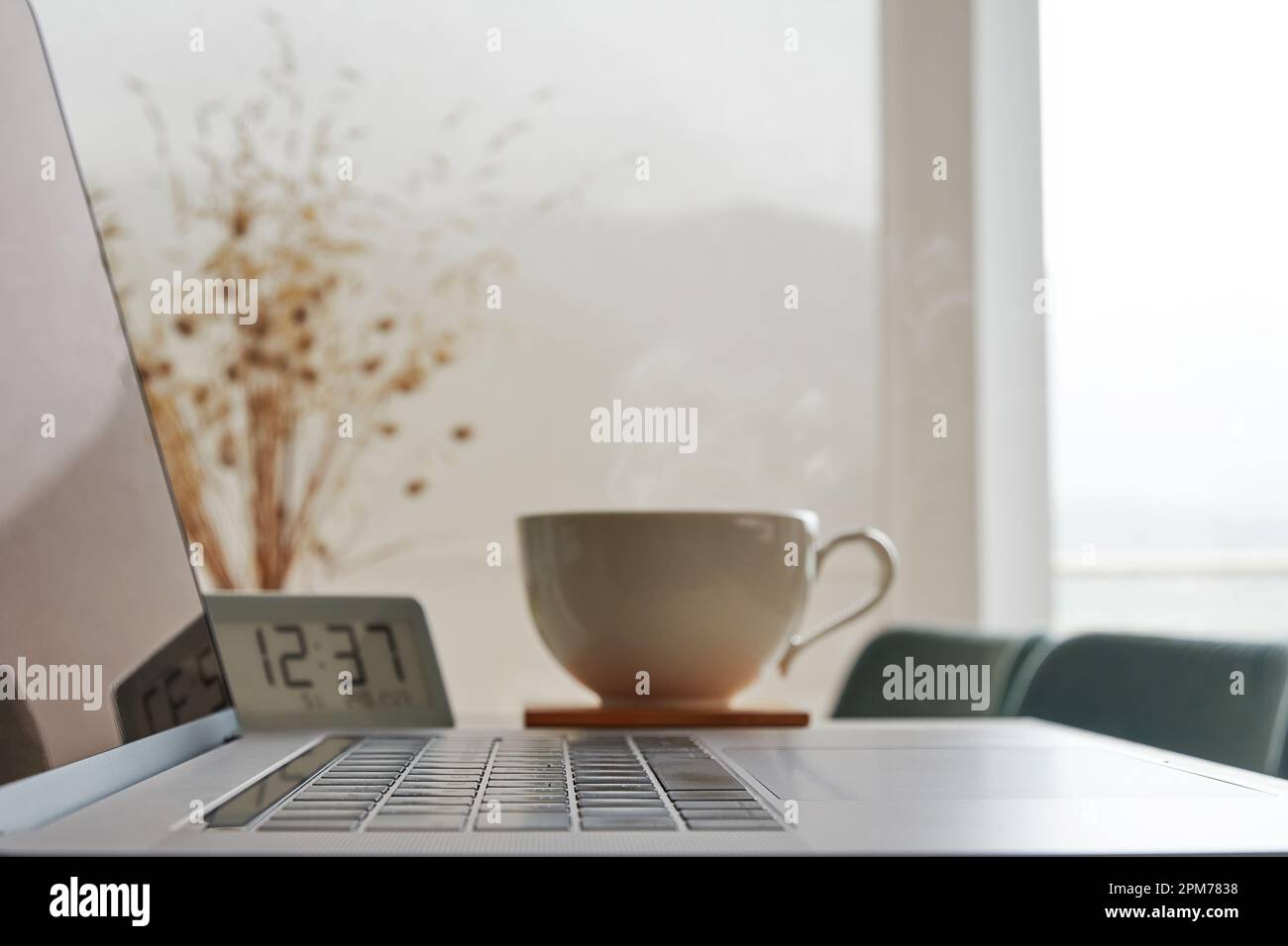 Modern working laptop on the table with coffee cup and digital clock ...