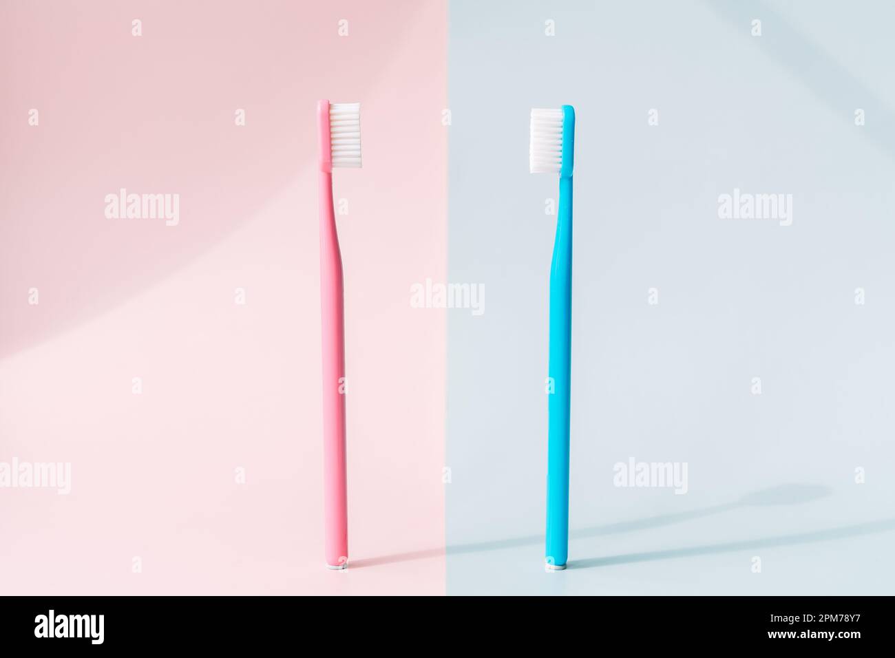 Pink toothbrush against pink background and blue toothbrush against ...