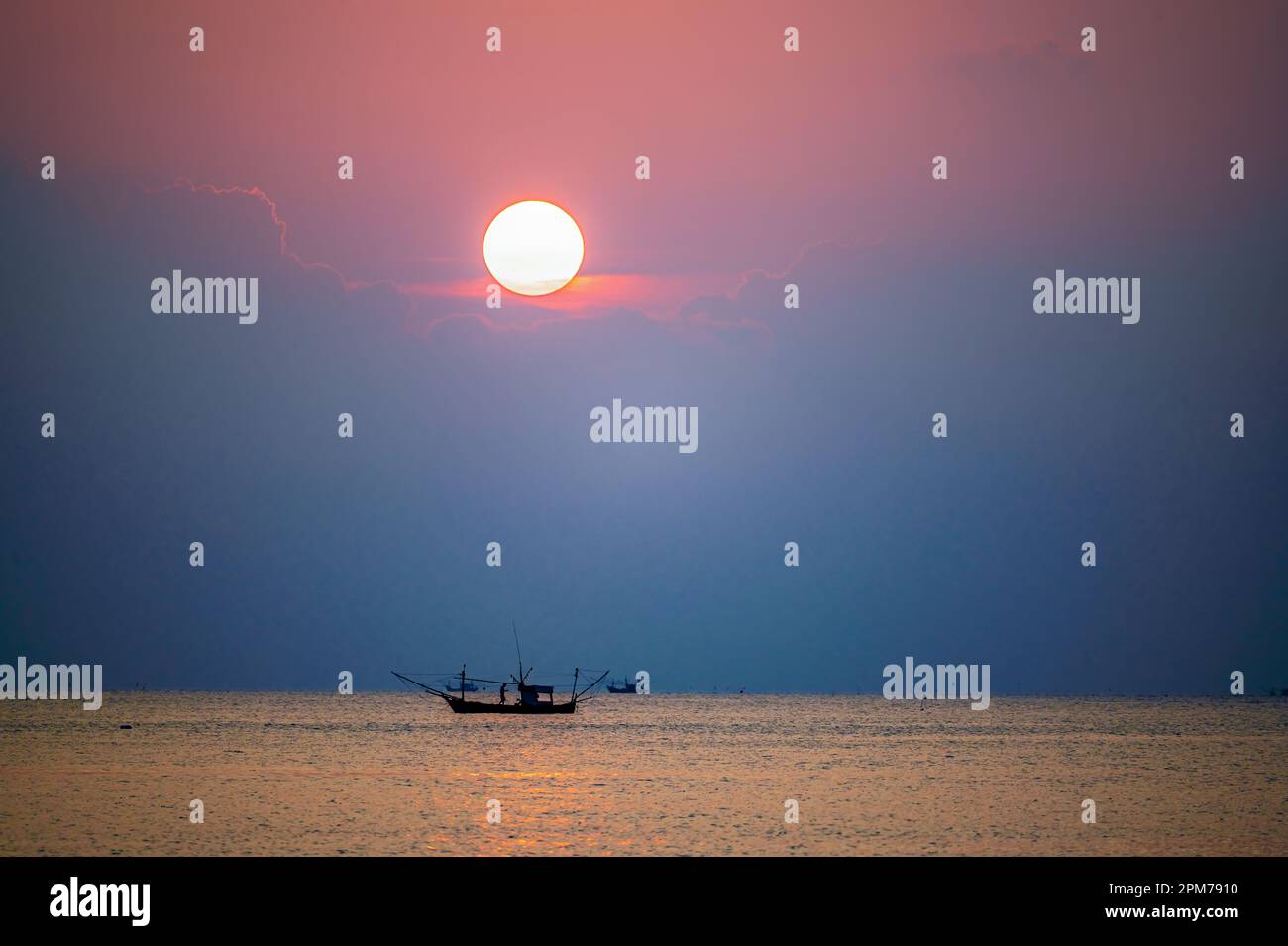 Picturesque sunset, silhouette of small fishing ship in front of sun ...