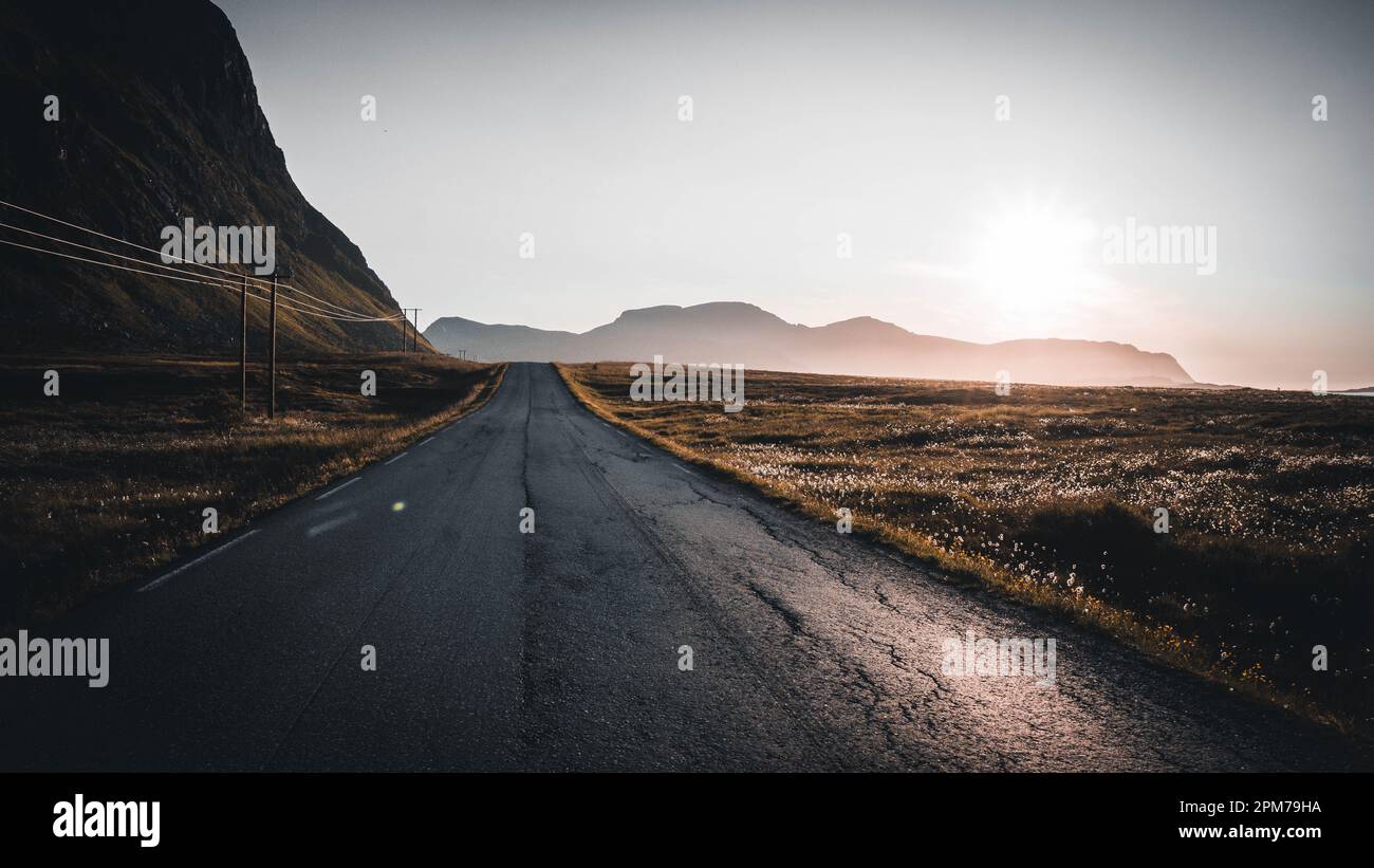 A scenic view of a winding road in a lush valley at sunset at a bright ...