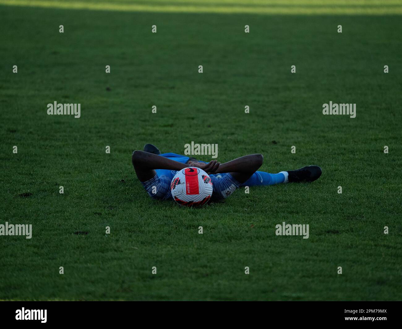 A young male soccer player relaxing in a grassy field near a ball Stock ...