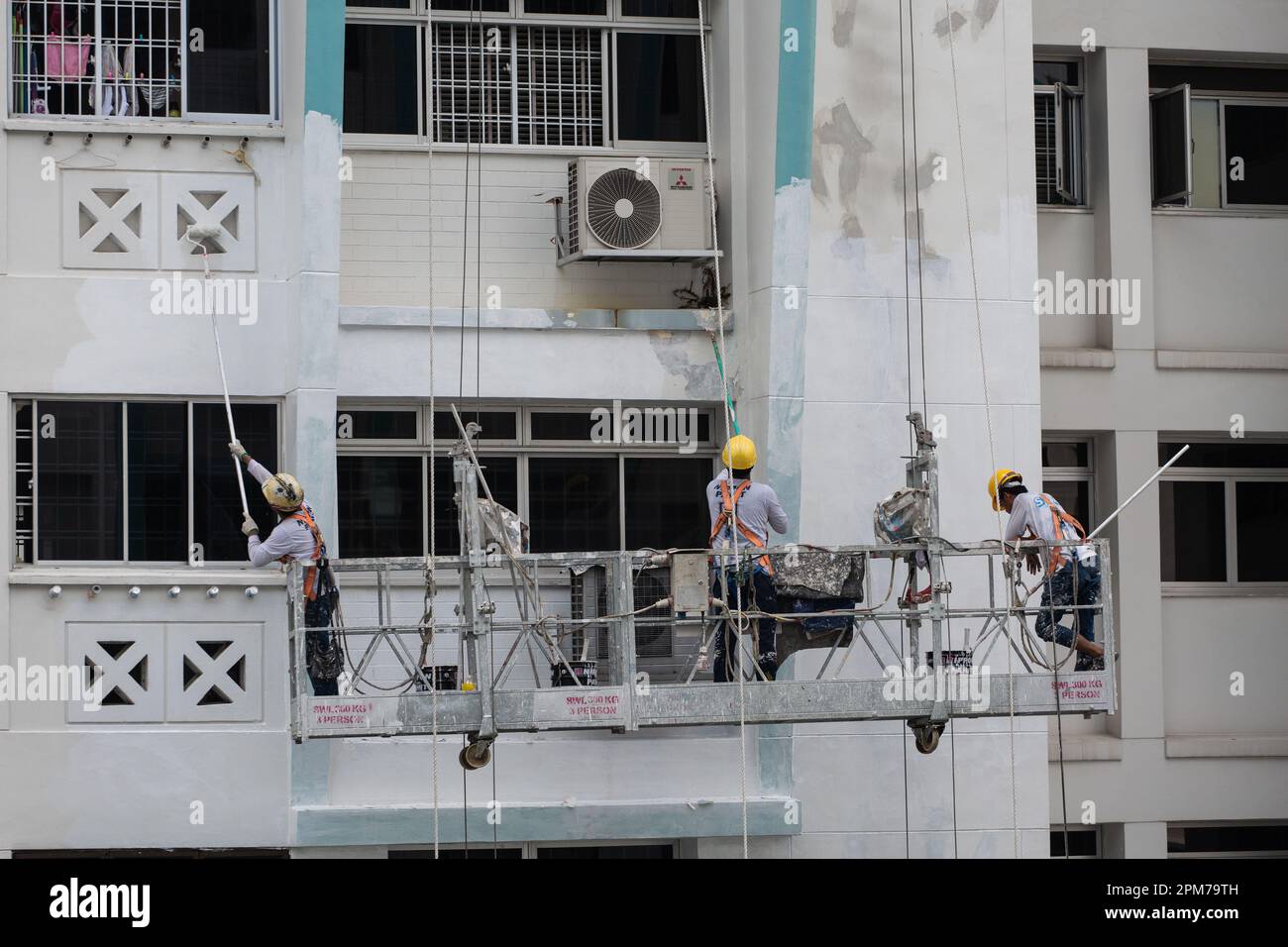 Three workers on the scaffolded elevators in height, working their best ...