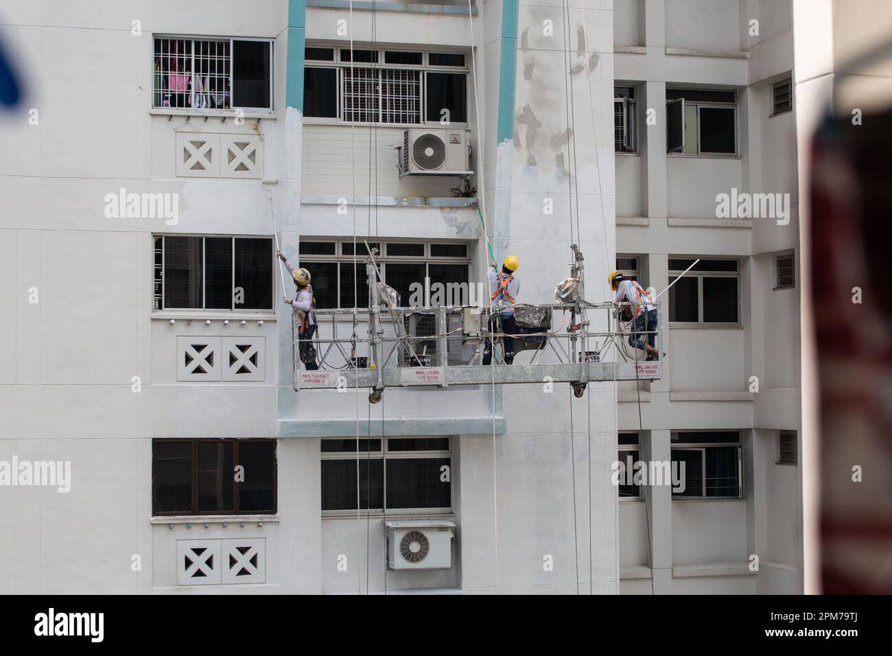 Three workers on the scaffolded elevators in height, working their best ...