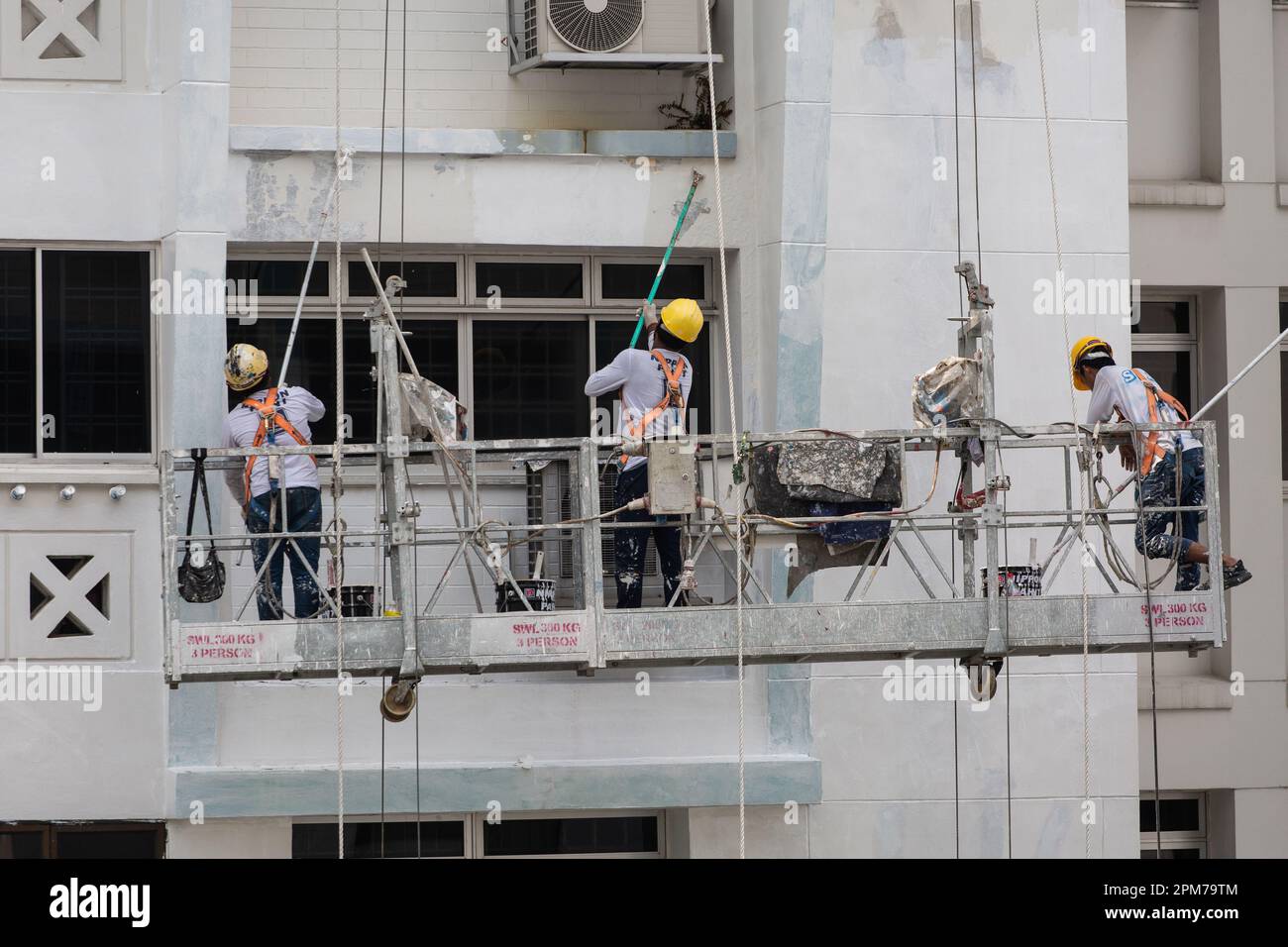 Three workers on the scaffolded elevators in height, working their best ...