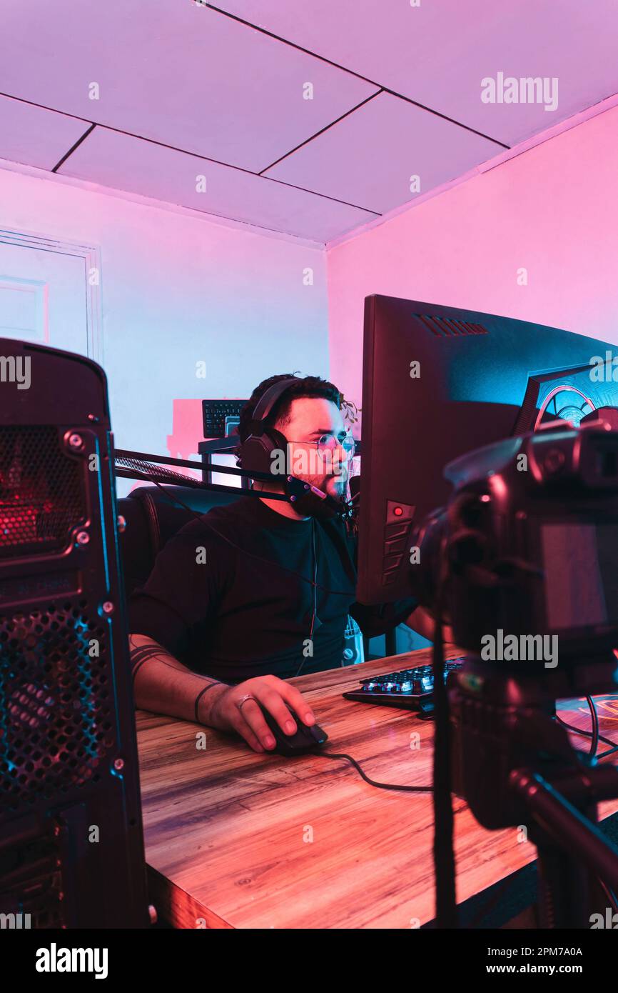 A vertical shot of a male streamer playing video games on his monitor ...