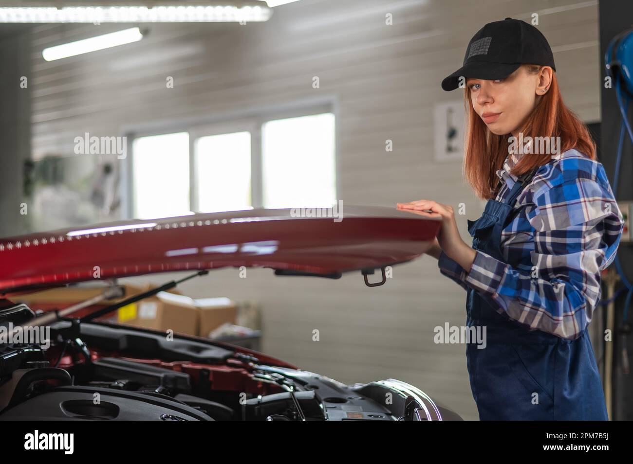 Woman auto mechanic opens the hood of a car in a car service Stock ...