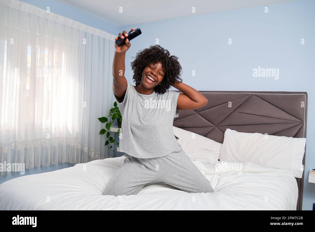 Happy african young woman dancing in bed because weekend start Stock ...