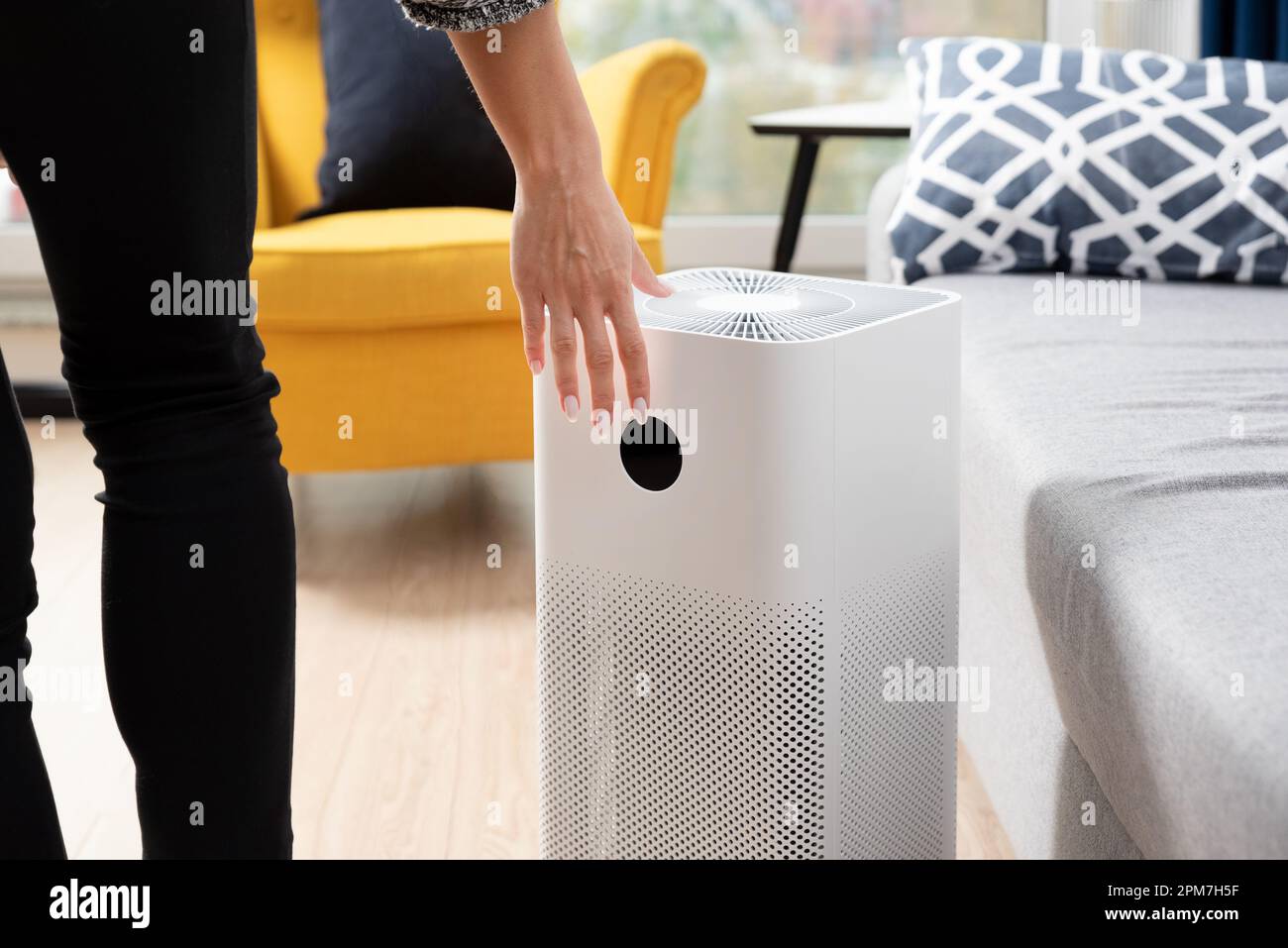 Woman using air purifier, fresh air at home Stock Photo - Alamy