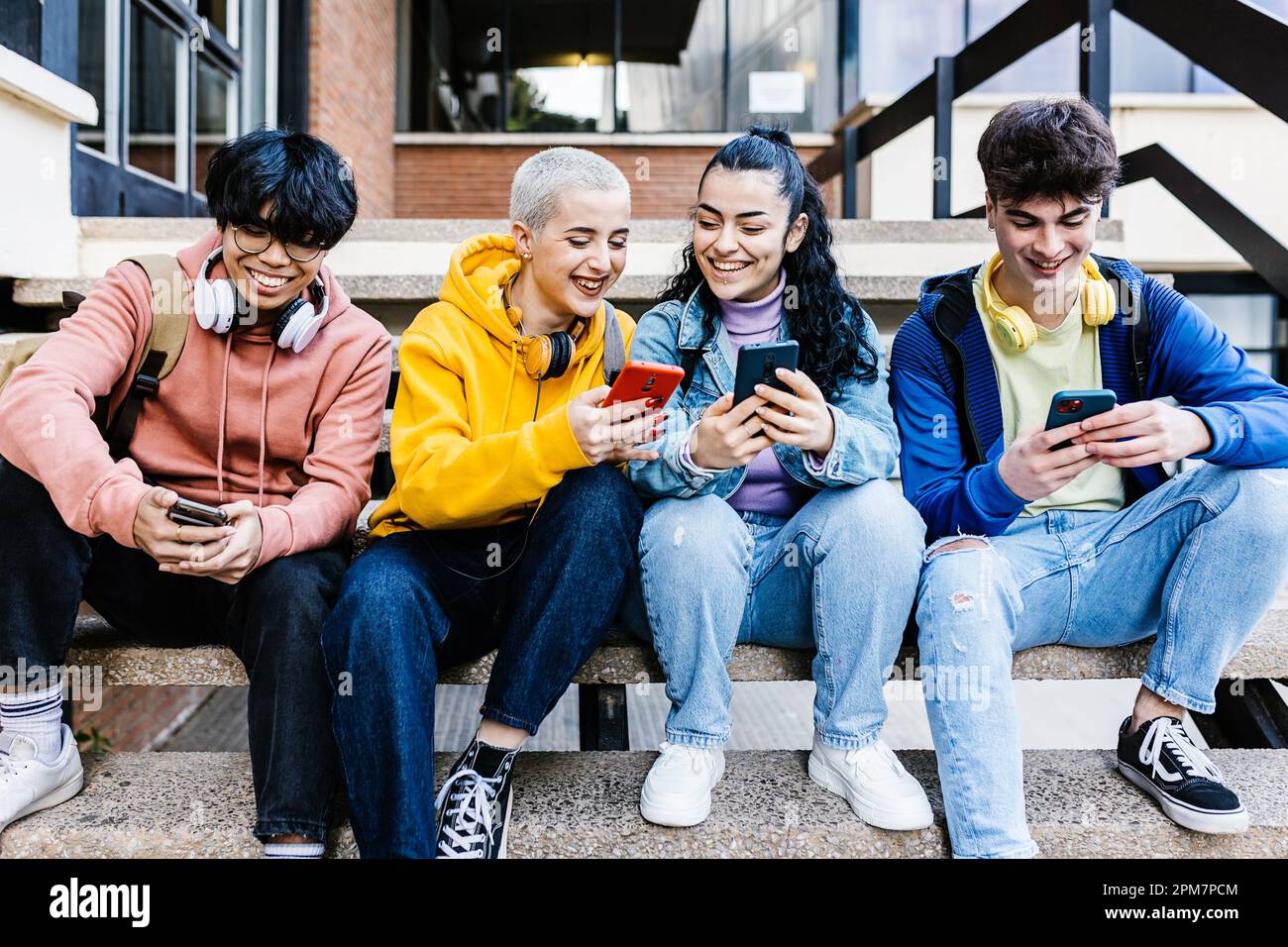 Happy multiracial group of high school students using mobile phones ...