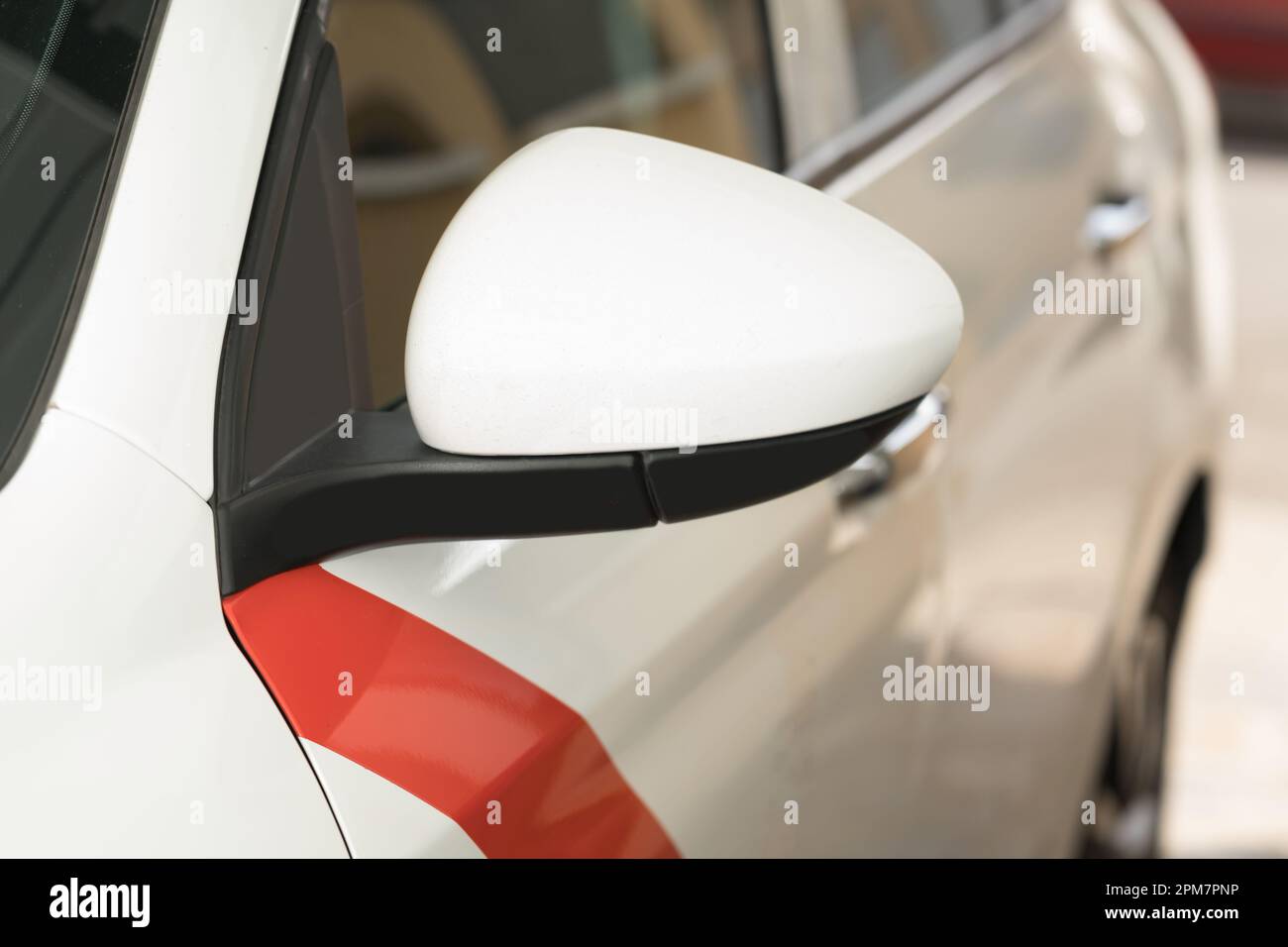 A close-up view of a white car mirror with a bright red stripe across ...