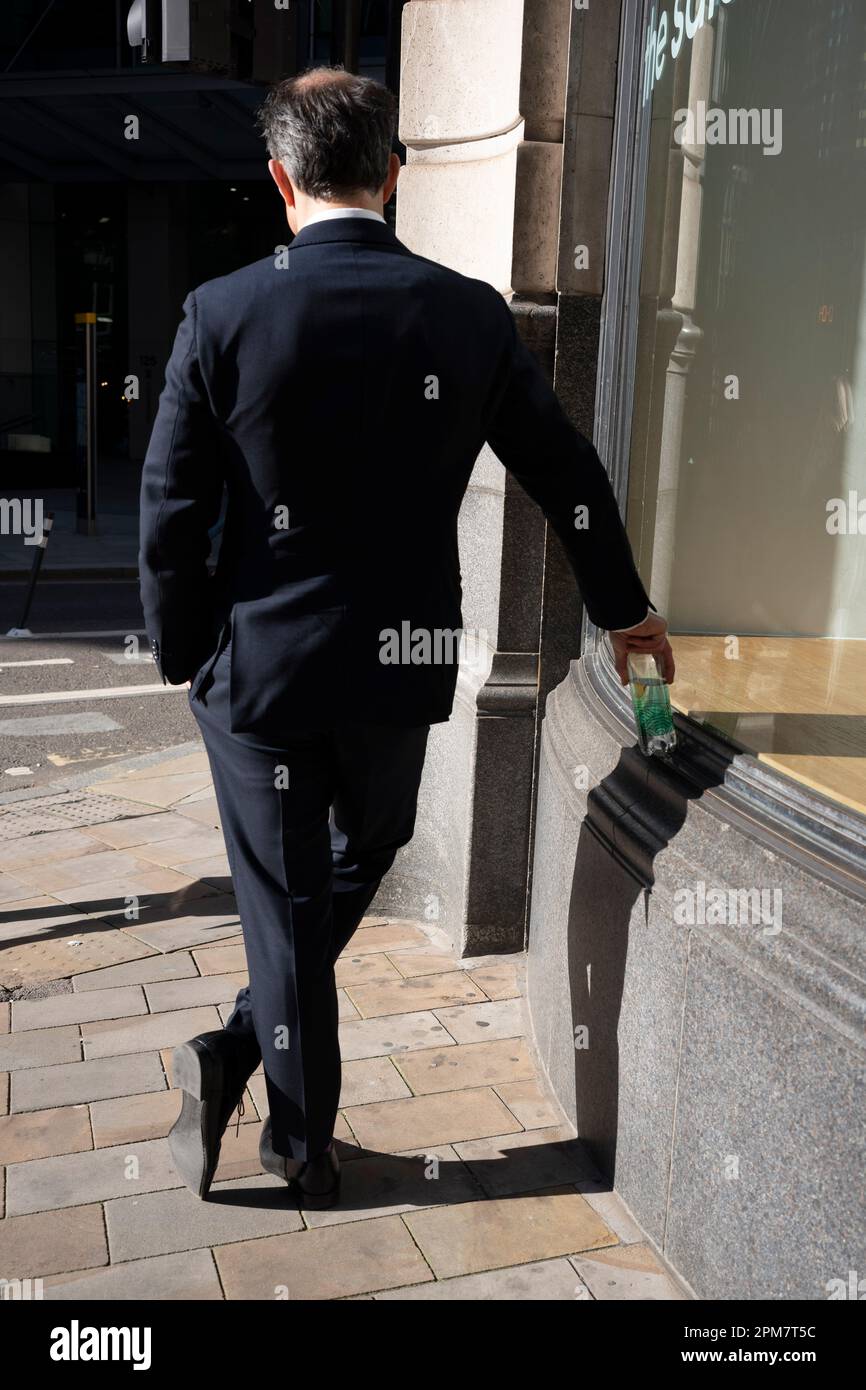 A rear view of a businessman standing on his own at a street corner in ...