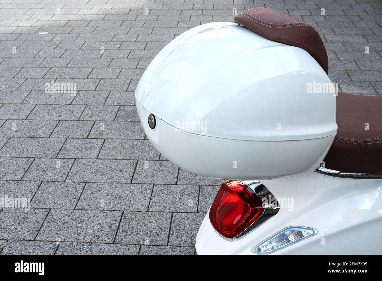 Part of a moped with a white plastic trunk and brake light. Close up ...
