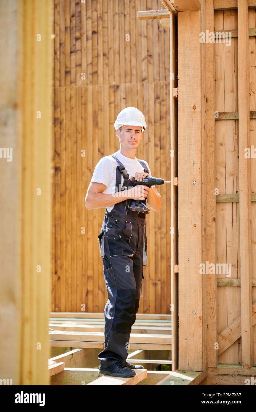 Carpenter constructing wooden framed house. Man worker cladding facade ...