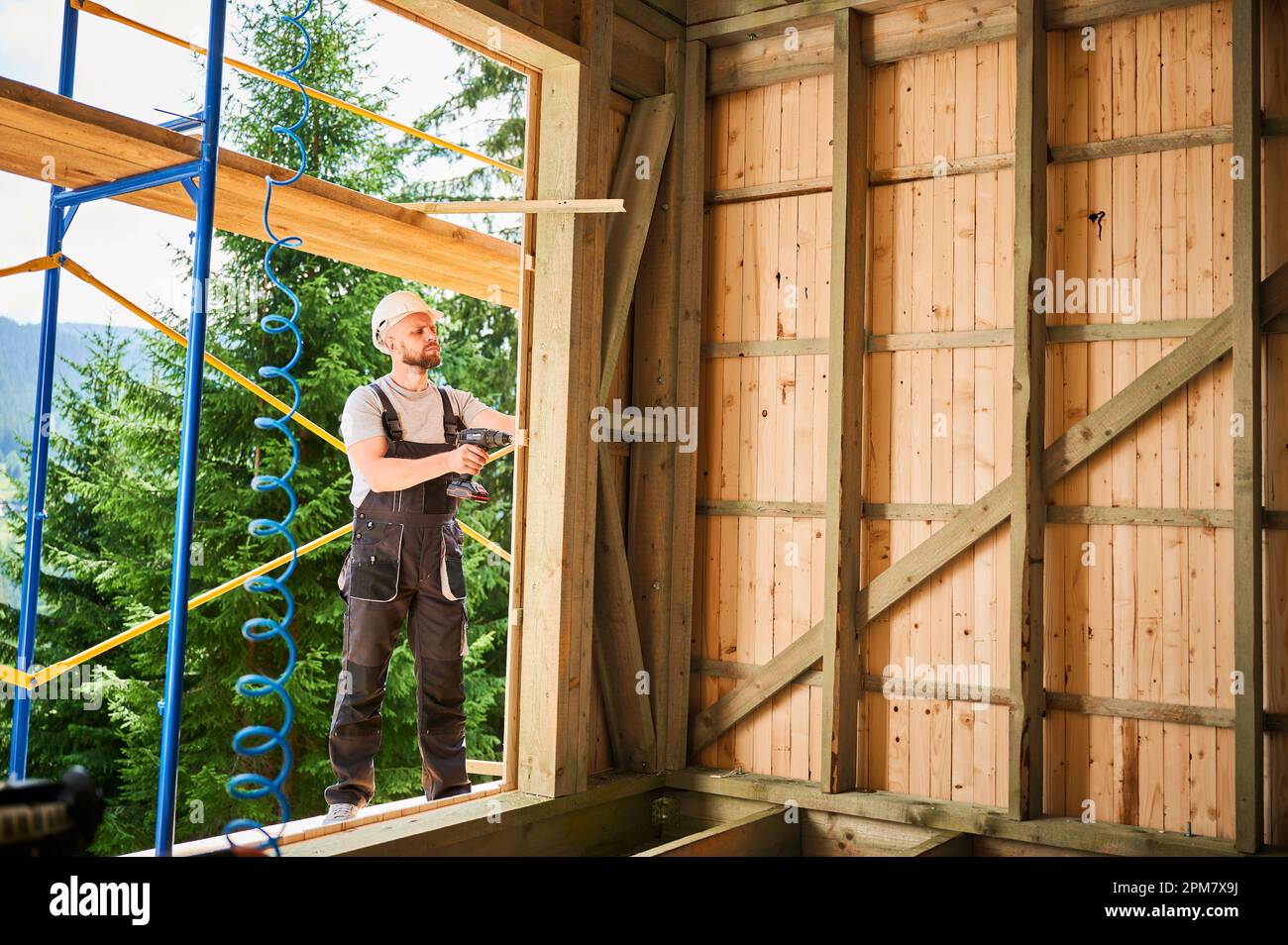 Carpenter constructing wooden framed house. Bearded man worker cladding ...