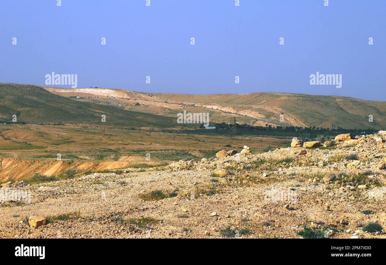 On the foreground, a sandy land of a desert is illuminated by the ...