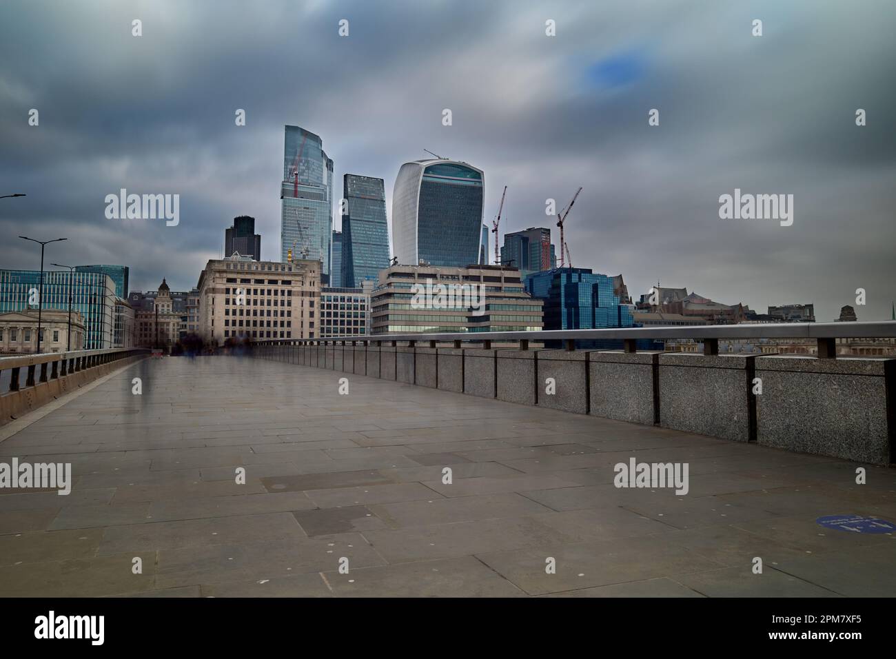 The City of London from London Bridge, under a dark oppressive sky. A ...
