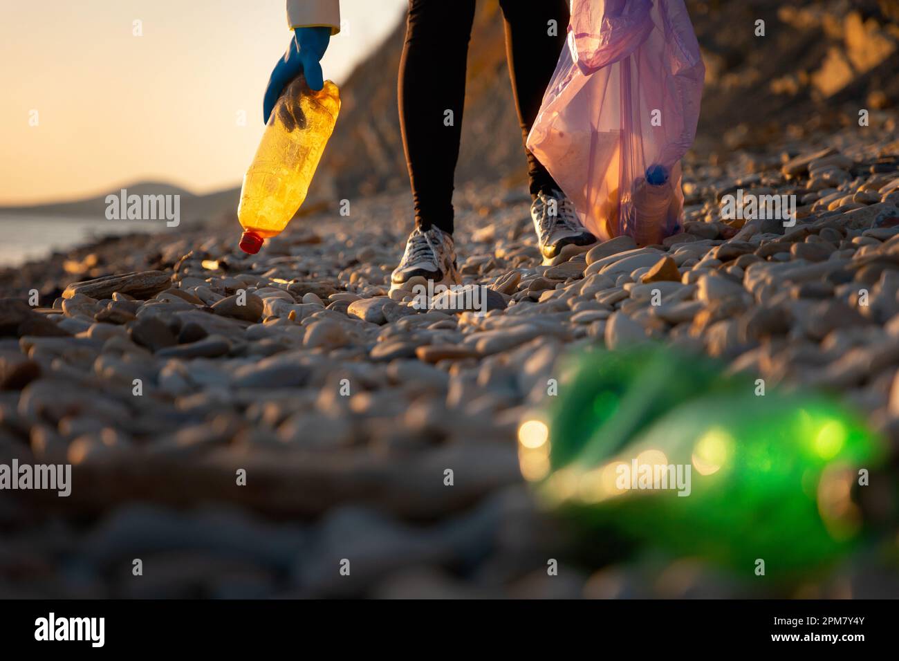 Waste recycling and social problems. A volunteer walks along a pebble ...