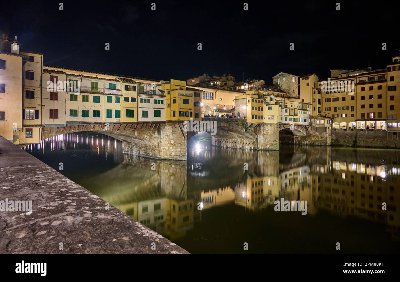 night shot of illuminated medieval brigde Ponte Vecchio over Arno river ...