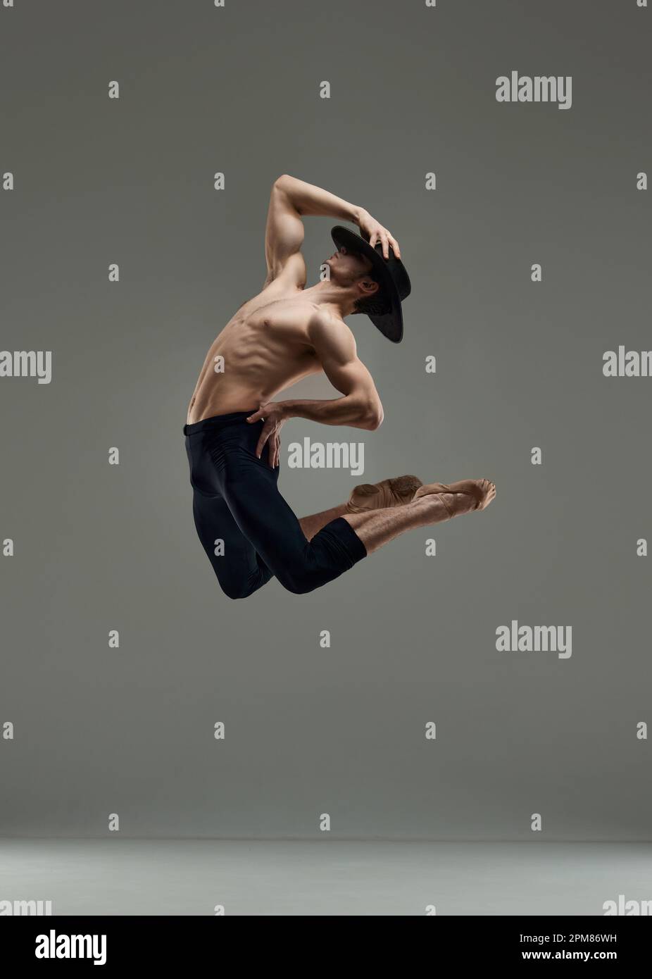 Handsome young man with muscular body dancing in hat and trousers ...