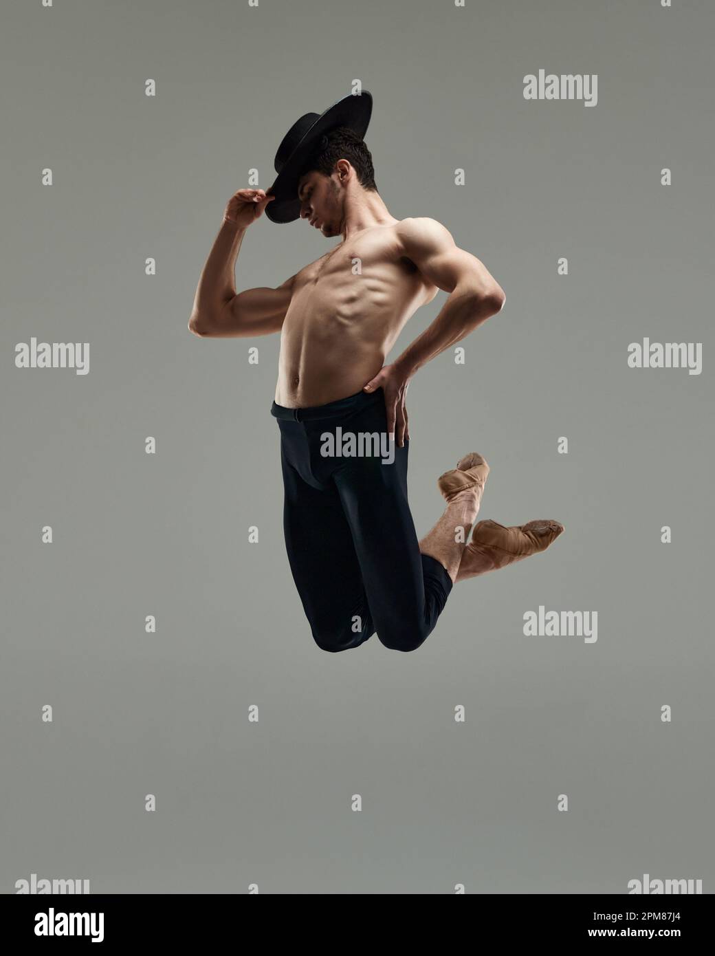 In a hump. Handsome young man, ballet dancer in hat and trousers ...