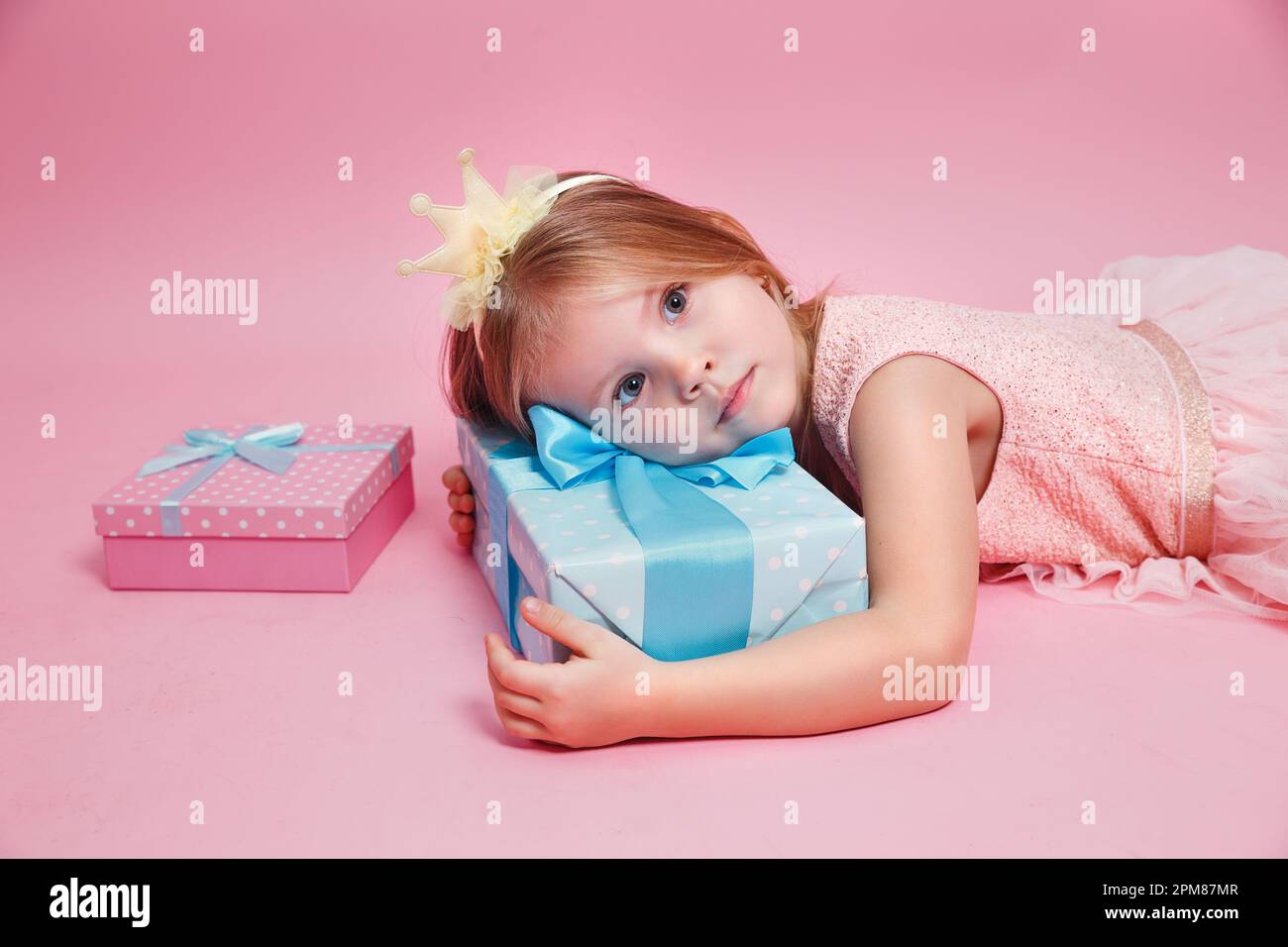 Cute sweet little princess wearing pink dress hugging present boxex and ...