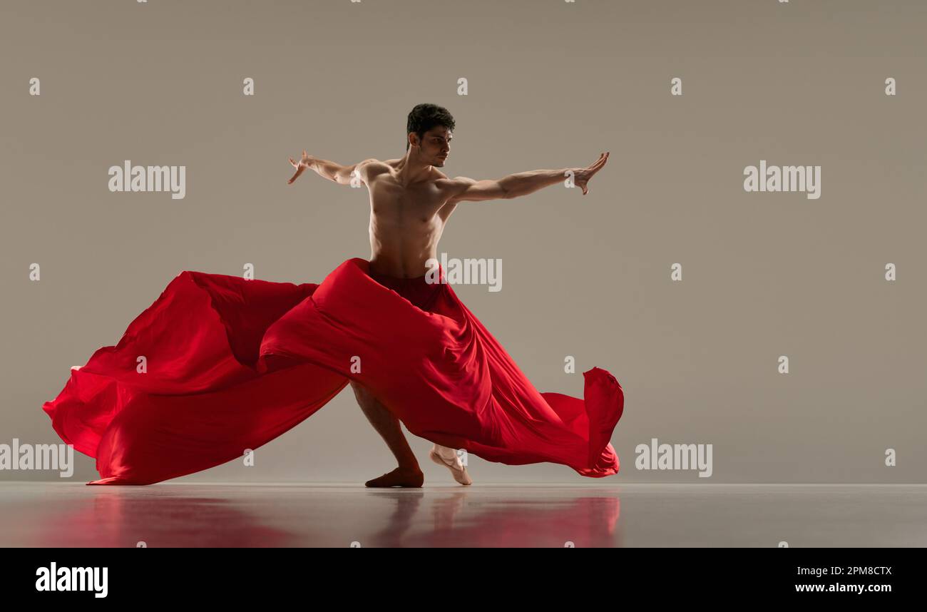 Young, talented, handsome man, ballet dancer dancing with red silk ...