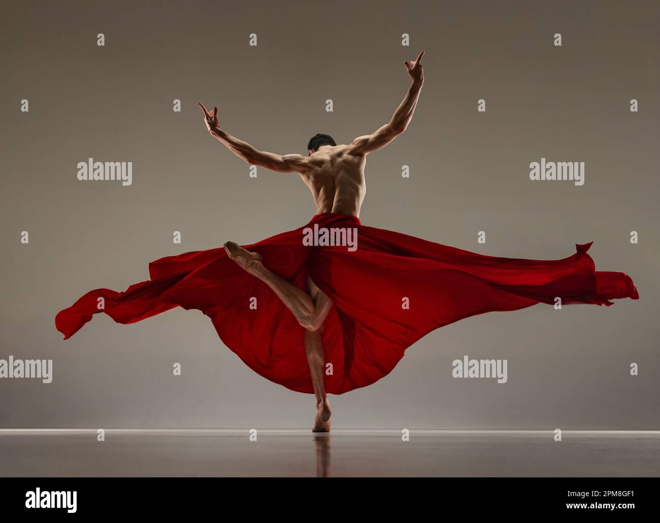 Talented performance. Handsome man, ballet dancer dancing with red silk ...