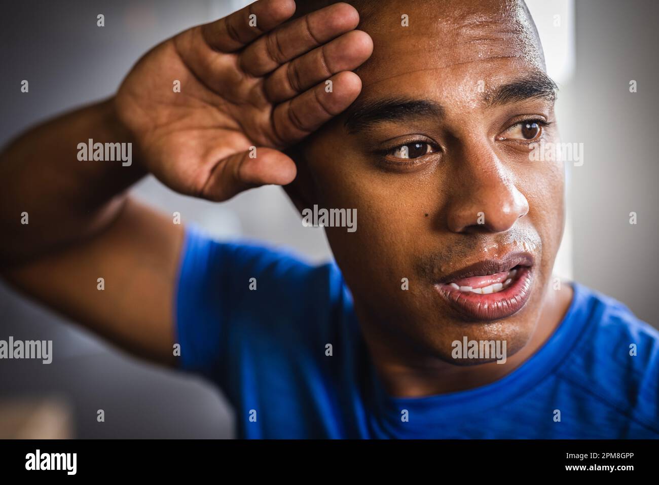 Closeup of tired biracial young man wiping sweat from forehead while ...