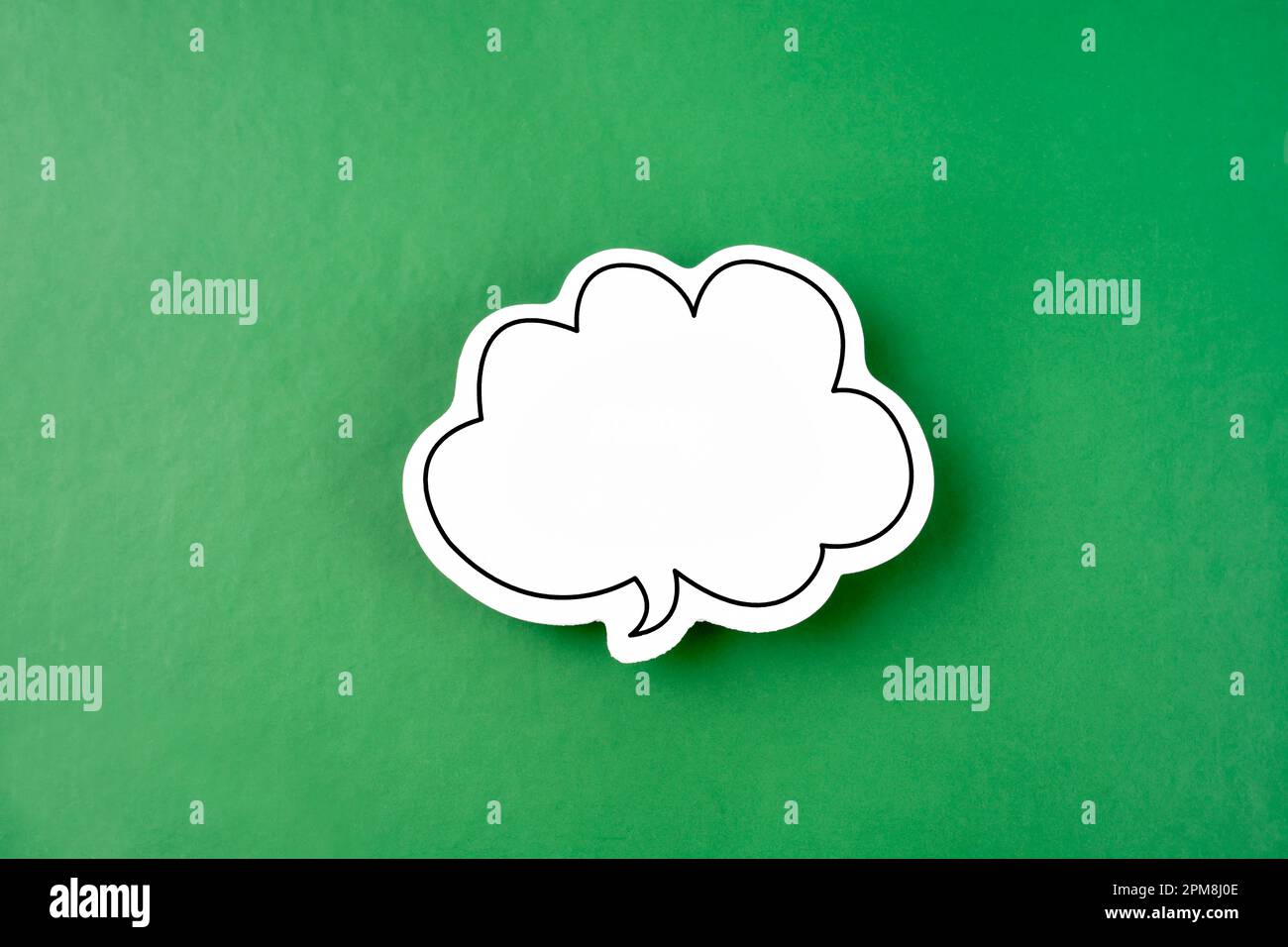 White speech bubble shaped post it note on green background with copy ...