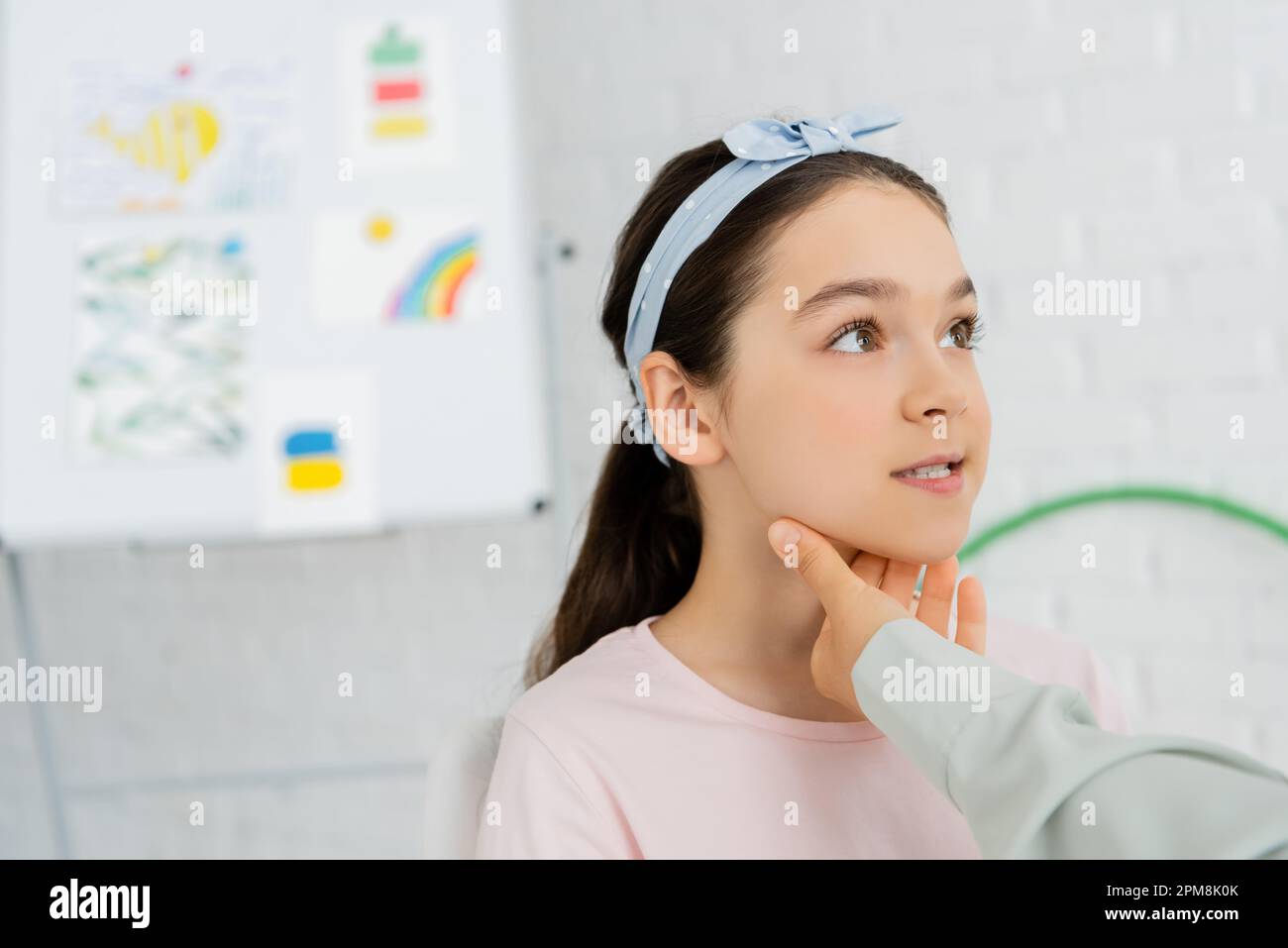 Speech therapist touching neck of preteen child during lesson in ...