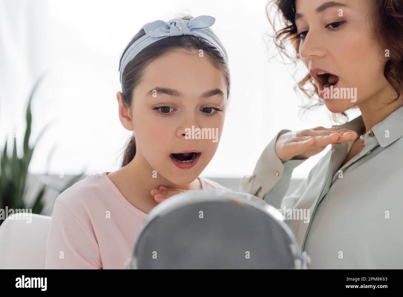 Speech therapist and child talking near blurred mirror in consulting ...