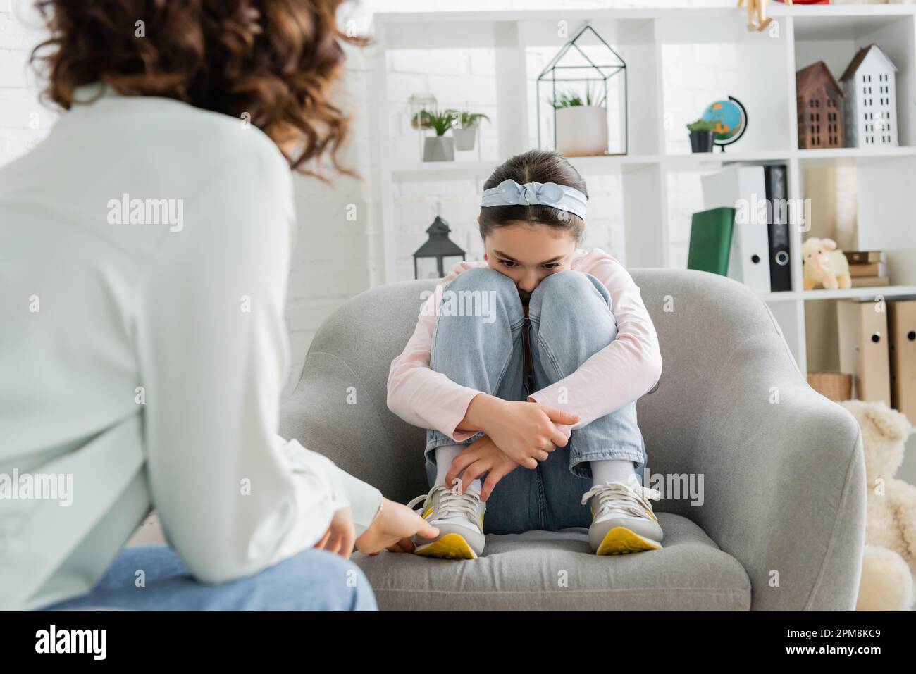 Disappointed preteen kid sitting on armchair near psychologist in ...