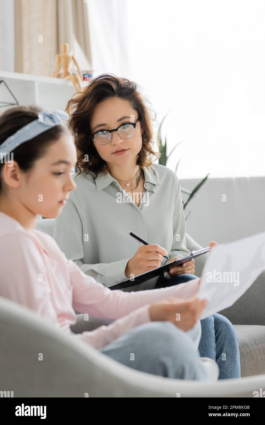 Psychologist writing on clipboard near child with Rorschach test in ...