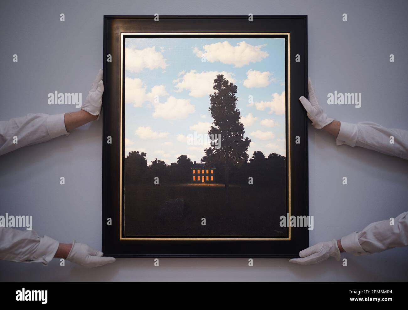 Gallery technicians holding a painting by Rene Magritte, L'Empire des ...