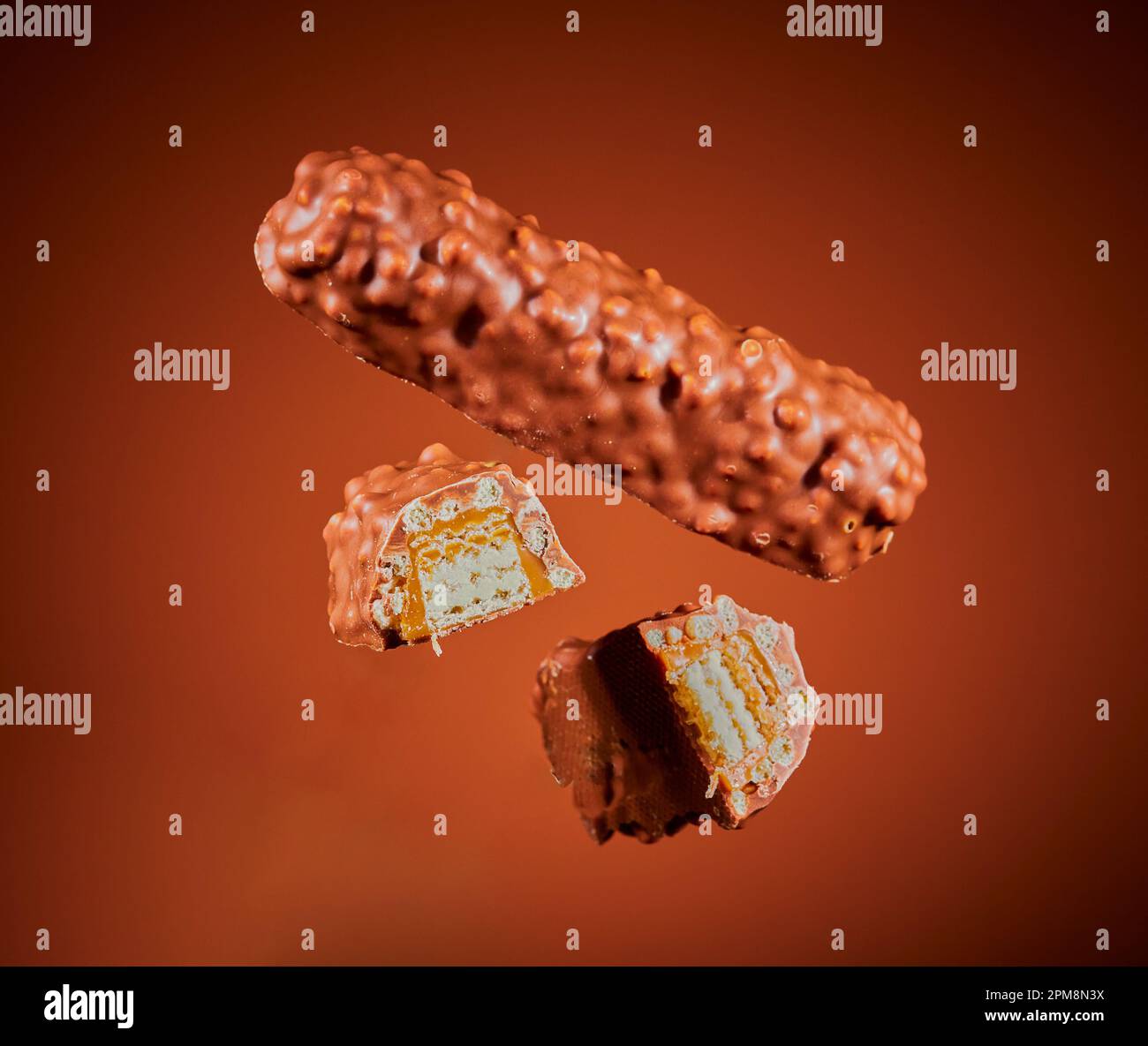 Crispy wafer coated chocolate bar suspended in the air with a brown ...