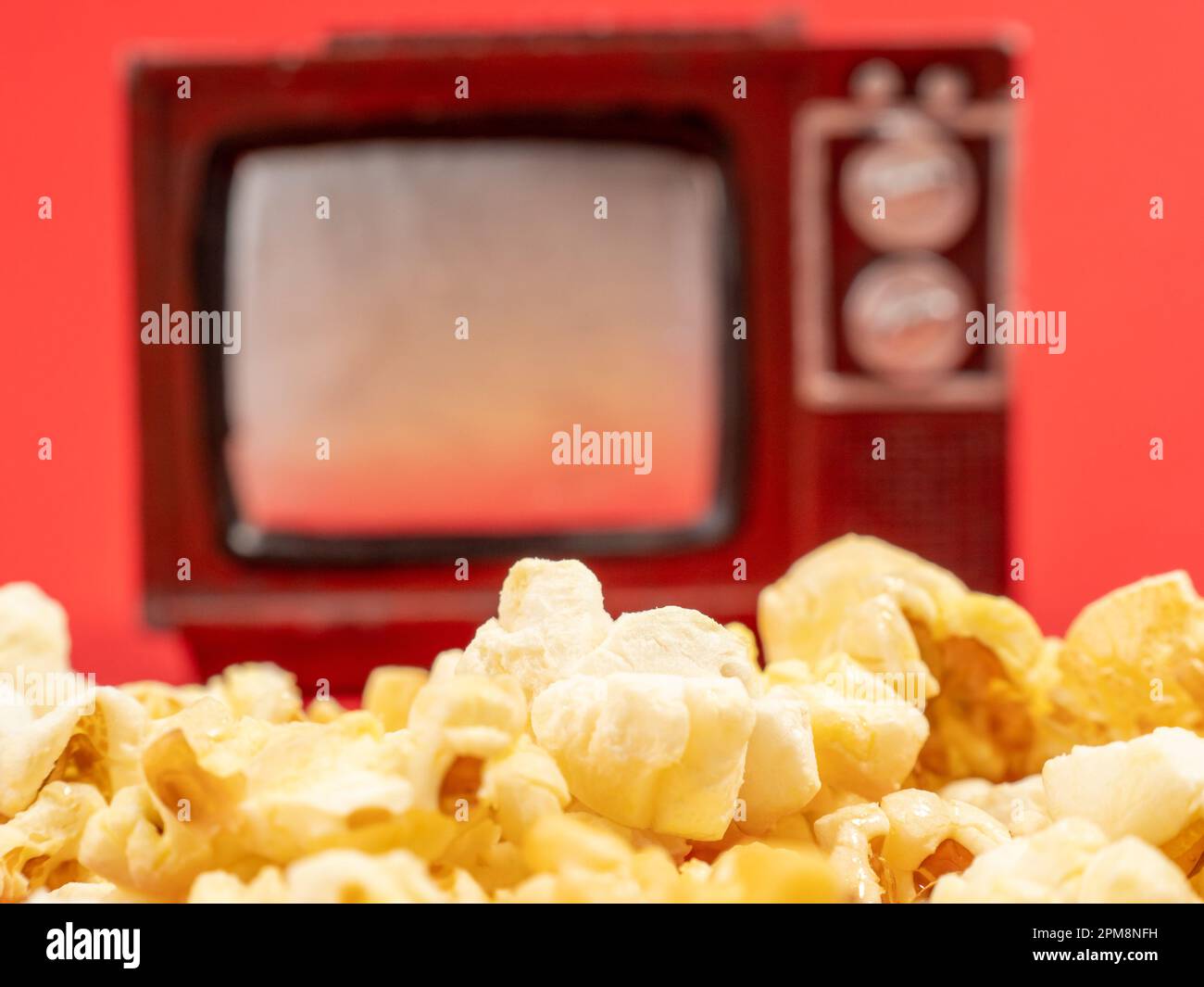 Popcorn and an old TV on a red background. Sweet popcorn on red. Close ...