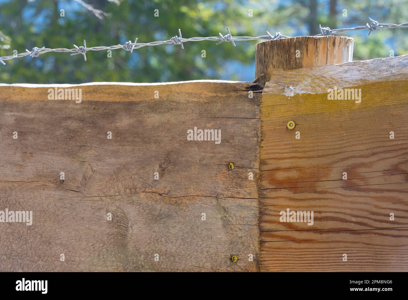 Extreme close up of wooden rustic solid fence barbed stretched above ...