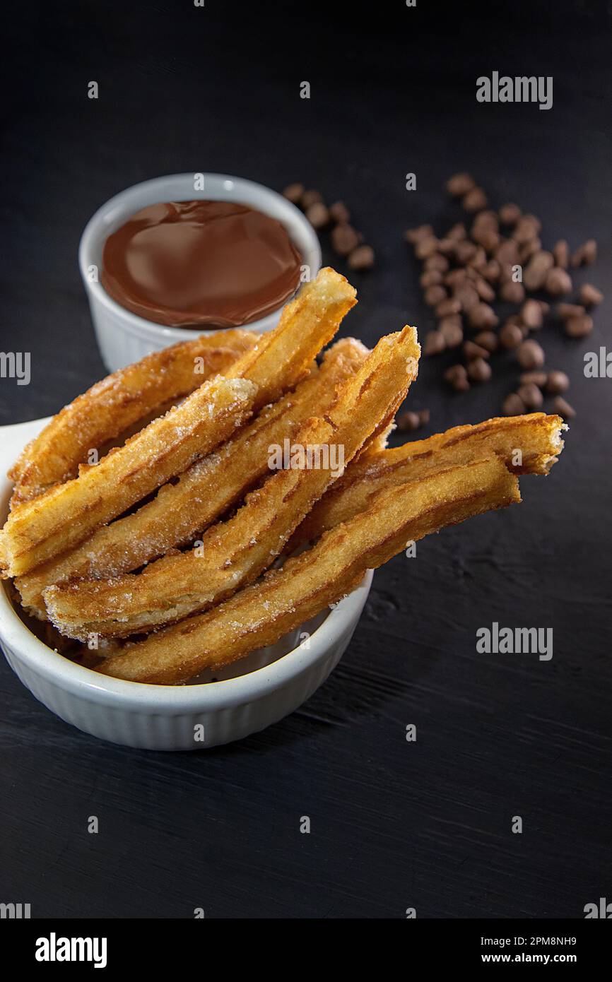 A vertical image of traditional Spanish churros with a side of creamy ...