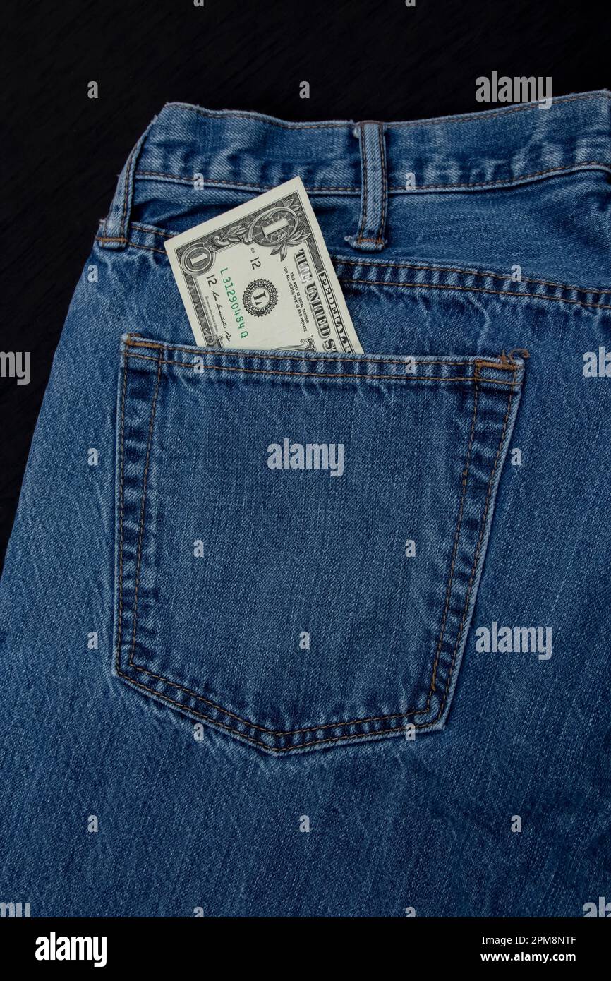 A vertical image of a pair of blue jeans with cash visible in the ...