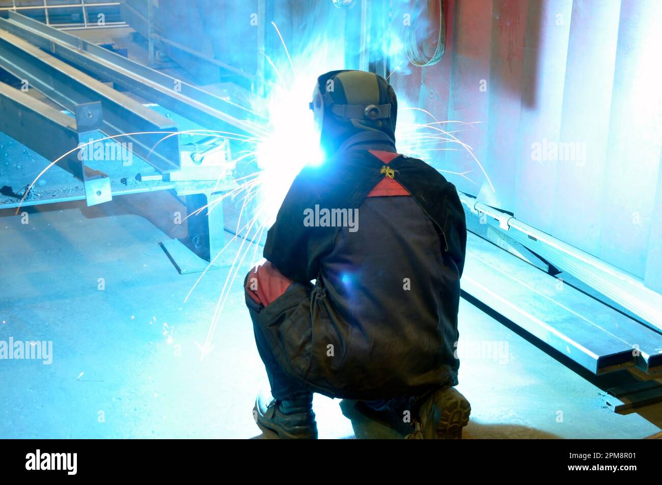welding metal ideas in a forced position, kneeling Stock Photo - Alamy