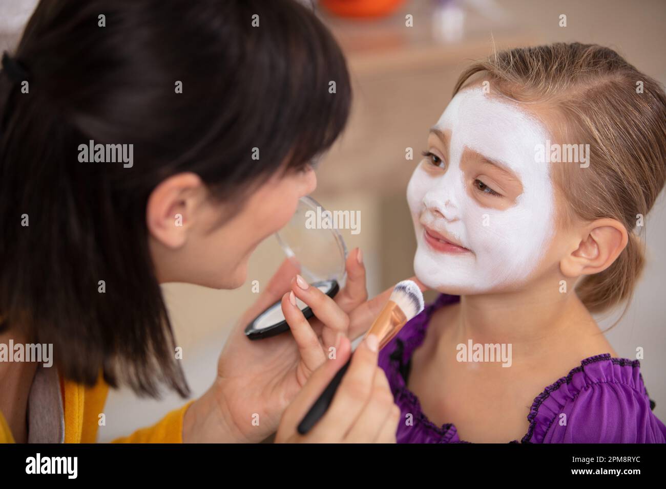 mum applies face paint to daughters face Stock Photo - Alamy